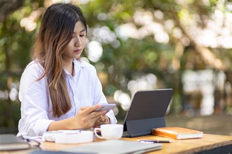 캐주얼 한 옷을 입은 야외 비즈니스 여성은 자연스럽고 편안한 환경에서 노트북과 현대적인 장비로 작업하고 있습니다 20 24세에 대한 스톡 사진 및 기타 이미지 Istock