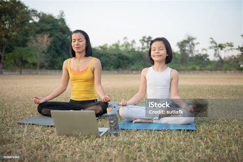 어머니와 딸이 요가를하고 있습니다 공원에서 여자와 어린이 훈련 야외 스포츠 건강한 스포츠 라이프 스타일 요가 운동 하는 동안 온라인 비디오 자습서 및 명상 연습을 보고 2