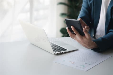 Businessman Using A Calculator To Calculate Numbers On A Company S