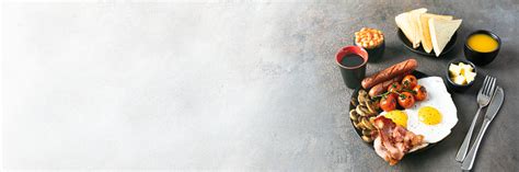 어두운 콘크리트 배경에 전형적인 영국식 아침 식사 계란 후라이 소시지 베이컨 콩 버섯 토스트 버터 커피 오렌지 주스 복사 공간이 있는 배너 가득 찬에 대한 스톡 사진 및