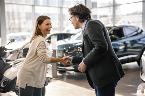 남성 자동차 판매자와 악수하는 이빨 미소를 가진 여자 둘 다 자동차 딜러에서 실내에서 서로 옆에 서 자동차 판매원에 대한 스톡 사진 및 기타 이미지 Istock