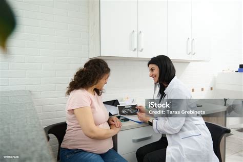 여성 의사 Gp 산부인과 의사가 의료 상담에서 임산부에게 아기의 초음파 검사를 보여줍니다 2명에 대한 스톡 사진 및 기타 이미지