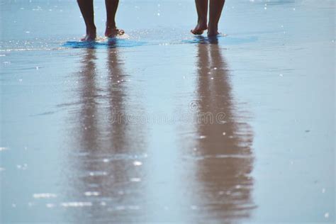People Walk On The Beach The Reflection Of The Feet On The Wet Ground