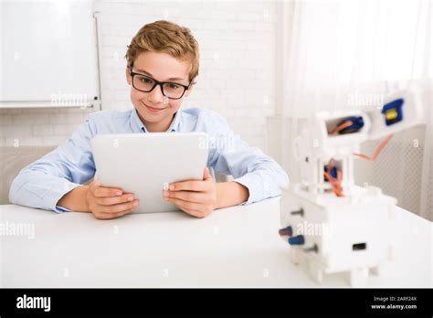 Smart Boy Programming Robot With Tablet At Stem Educational Lesson