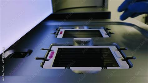 Dna Sequencer Gloved Hand Is Handling Flow Cell With Multiple Lanes For Dna Samples Placed
