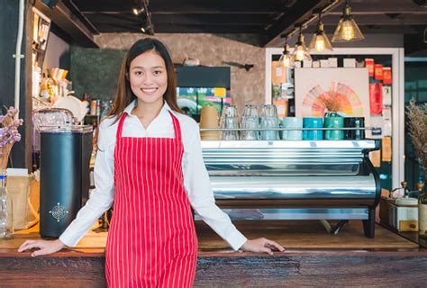 미소 얼굴 카페 서비스 개념 카운터 바에서 아시아 여성 바리 스타 착용 빨간 앞치마 소유자 비즈니스 시작 합니다 기계류에 대한