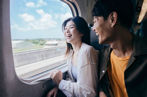 동양인 커플은 기차 창밖으로 보이는 풍경을 설레는 마음으로 바라보며 그들의 얼굴에는 기대와 기쁨이 반영되어 여행의 스릴을