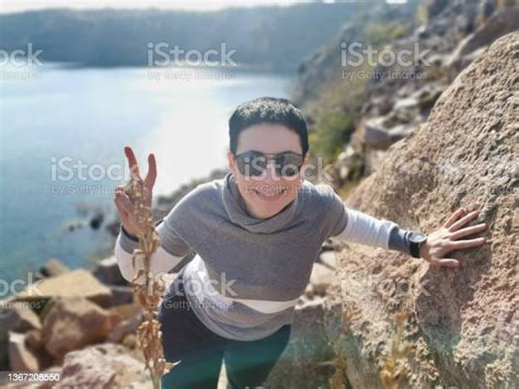 สีน้ําตาลที่สวยงามบนชายฝั่งหินของทะเลสาบ ผู้หญิงในชุดกีฬาและแว่นตากันแดดสีดํา ภาพสต็อก ดาวน์