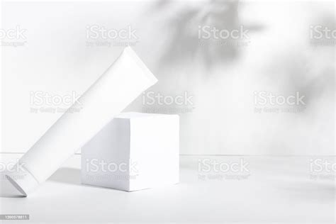 나뭇잎과 그림자가 있는 스탠드에 흰색 화장품 튜브 치약 얼굴 바디 크림 스킨 케어 제품이 있는 여성 화장품 튜브 유기농 화장품