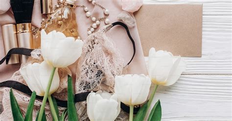 세련 된 여성 세트입니다 레이스 란제리 보석과 향수 인사말 카드는 부드러운 천과 흰색 소박한 배경에 튤립에 있습니다 휴가를 위한 플랫 레이 소녀 필수품 텍스트 공간