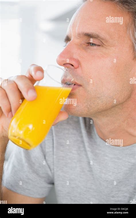 Content Man Drinking Orange Juice In Kitchen Stock Photo Alamy