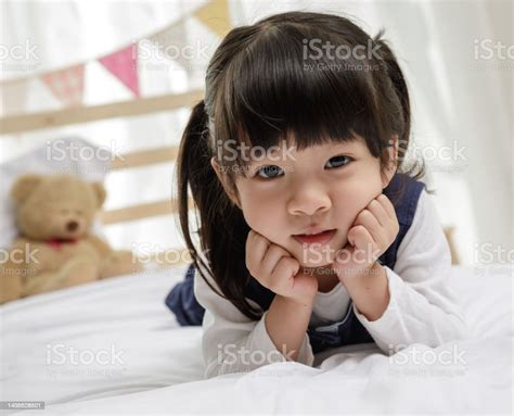 아이 소녀는 위장에 누워 미소 행복한 아시아 아이 어린 소녀는 그녀의 침실에서 나무 침대에서 재생 행복한 가족 개념 2 3 살에