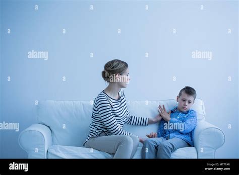 Serious Mother And Her Autistic Son Sitting On A Sofa Stock Photo Alamy