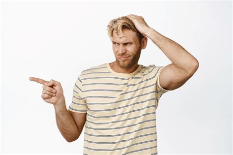 Free Photo Portrait Of Displeased Blond Man Pointing And Looking Left Showing Something