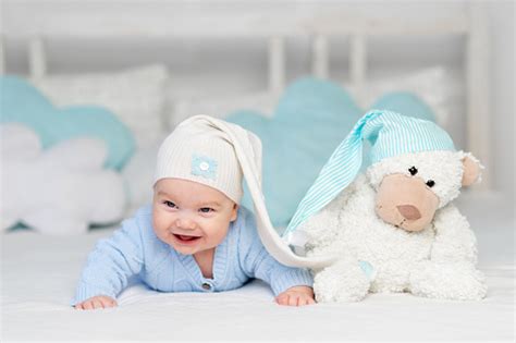 후드를 입은 침대에 누워 있는 아기가 잠자리에 들거나 아침에 깨어나게 됩니다 어린이를위한 섬유 및 침구 장난감 곰을 가진 신생아 6 11 개월에 대한 스톡 사진 및 기타