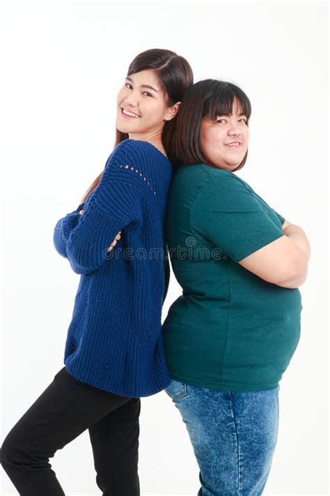 Two Fat And Skinny Asian Girls Having Fun Enjoying Sea Tourism Sitting On The Beach Stock Photo