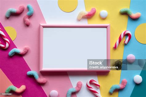 겹겹이 쌓인 색종이에 빈 분홍색 흰색 프레임 다양한 과자 과자 초콜릿 및 사탕 지팡이가 복사 공간이있는 빈 프레임 주위에 텍스트를 놓을 수 있습니다 플랫 레이 평면도 사탕에