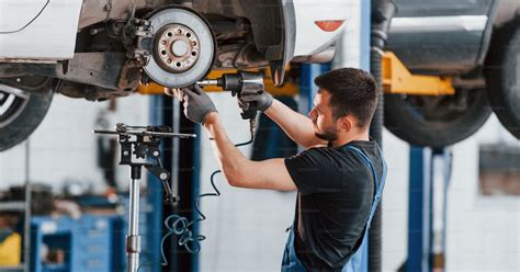 특수 도구 사용 작업복을 입은 남자가 실내에서 흰색 자동차를 수리합니다 자동차 서비스의 개념 사진 Unsplash의 우크라이나 이미지