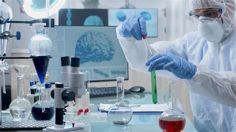 병원 실험실에서 미생물학 실험 중에 액체 용액을 혼합하는 의료용 투명 안경을 사용하여 화학 실험을 하는 Ppe 장비를 가진 연구원 화학자 의학 개념 프리미엄 사진