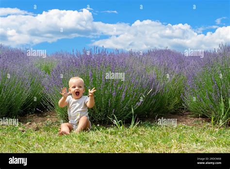 Baby Expressing Her Joy By Raising Her Hands While Sitting Down And In The Background Is A