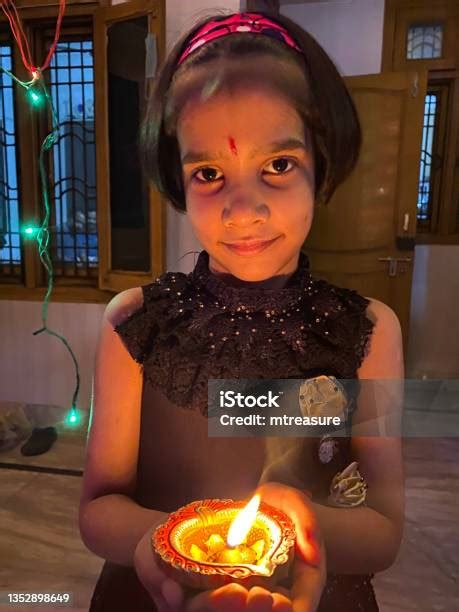 빛의 기름이 가득한 점토 디야를 손바닥에 들고 있는 인도 소녀의 이미지 불이 켜진 심지의 디왈리 오일 램프 어두운 불꽃 디왈리