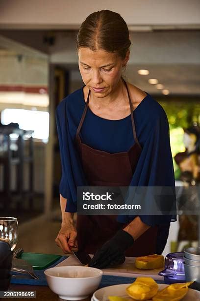 앞치마를 두른 여자가 부엌 환경에서 조심스럽게 음식을 준비하고 있습니다 35 39세에 대한 스톡 사진 및 기타 이미지 35 39세 가정 주방 가정의 방 Istock