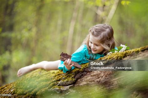 봄 나무에서 걷는 파란 드레스에 아름 다운 어린 소녀 예쁜 소녀는 텀블 다운 나무에 리 잉 여름에 야외에서 노는 아이 부활절 시간입니다 갈란투스에 대한 스톡 사진 및 기타