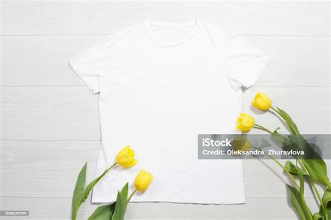 흰색 티셔츠 모형 템플릿 빈 셔츠 평면도입니다 흰색 나무 배경입니다 어머니 여성의 날 휴일입니다 노란 튤립 생일 꽃다발 꽃이 있는 여자 티셔츠 봄의 모습 여성 액세서리 0