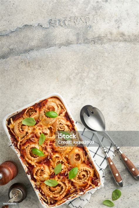 라자냐 수제 라자냐 파스타 로톨로는 가벼운 슬레이트 돌 또는 콘크리트 배경의 흰색 프라이팬에 토마토 소스 크림 치즈 및 바질로 굽습니다 이탈리아 요리 개념입니다 복사 공간이