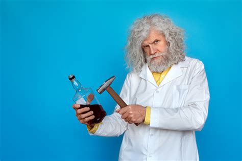 노인 을 입고 의사의 가운 스튜디오 고립 에 푸른 서 와 망치 가까운 병 의 위스키 찾고 카메라 적극적인 곱슬 머리에 대한 스톡
