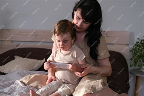 Mamá Y Su Hijo Pequeño Se Sientan En La Cama Y Miran Dibujos Animados