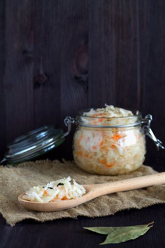 검은 색 배경에 유리 항아리와 나무 숟가락에 허브와 당근과 수제 소금에 절인 양배추 나무 테이블에 자루가 있는 양배추절임 복사 공간을 복사합니다 수직 채식 음식 건강한