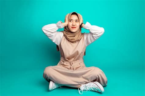 젊은 현대 이슬람 여성이 앉아서 트렌디한 캐주얼 옷을 입고 히잡을 사용합니다 프리미엄 사진