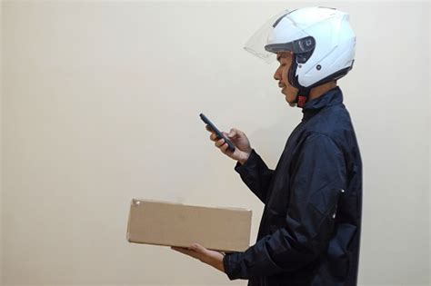 재킷과 헬멧을 착용 한 동남아시아 택배 남자 골판지 상자 운반 핸드폰 미소 복사 공간 크림 위에 포즈 취하기 개성 개념에 대한 스톡 사진 및 기타 이미지 Istock