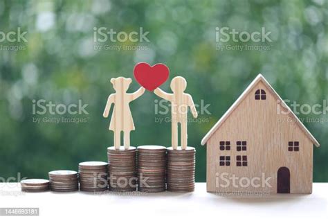 자연 녹색 배경에 모델 하우스와 동전 돈의 스택에 서 심장 모양을 들고 사랑 커플 연인이나 가족을위한 저장하고 미래의 개념에 준비를위한 돈을 절약 부동산에 대한 스톡 사진