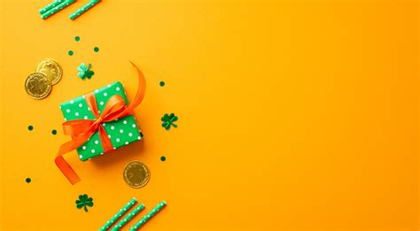 성 패트릭의 날 개념 주황색 활 빨대 금화 토끼풀 모양의 색종이가 있는 작은 녹색 선물 상자의 상위 뷰 사진 복사 공간이 있는 격리된 노란색 배경 3월에 대한 스톡 사진 및