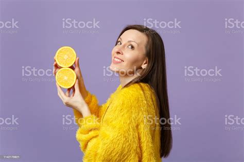 모피 스웨터에 잠겨있는 젊은 여자는 보라색 파스텔 배경에 고립 된 신선한 잘 익은 오렌지 과일의 Halfs 손을 잡고 찾고 사람들은 생생한 라이프 스타일 휴식 휴가