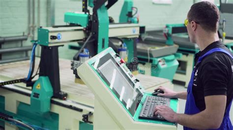 A Male Cnc Machine Operator Is Typing On The Control Panel Stock