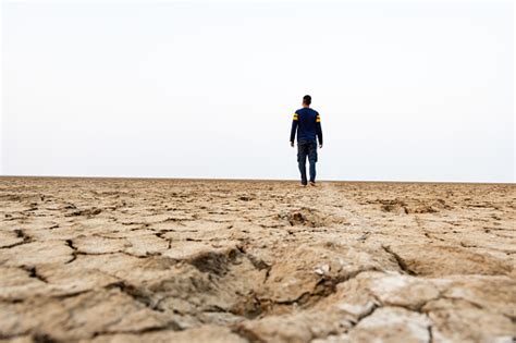건조하고 금이 간 농장 밭에 서 있는 농부는 낮은 각도에서 흐리게 초점을 맞춥니다 가뭄에 대한 스톡 사진 및 기타 이미지 가뭄 고독 개념 고독 부정적인 감정 표현
