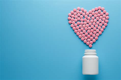 분홍색 비타민 B12 알 약 파란색 배경에 심장의 모양에 흰색 수 낮은 대비를 쏟아 0명에 대한 스톡 사진 및 기타 이미지