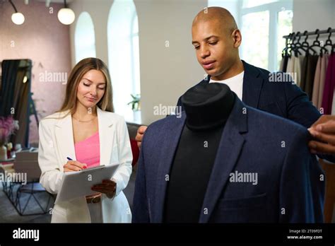 Tailor And His Assistant Taking Custom Made Clothing Measurements On