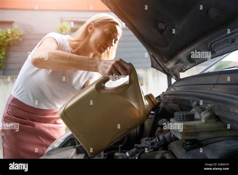 The Woman Pours Engine Oil Into Her Car Stock Photo Alamy