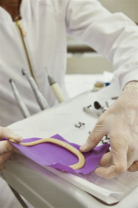 흰색 실험실 코트를 입은 사람이 종이 조각을 자르고 있습니다 사진 Unsplash의 치과 의사 이미지