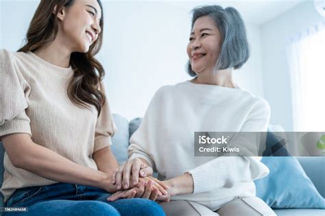 아시아의 사랑스러운 가족 어린 딸이 껴안고 나이 든 어머니와 함께 앉습니다 매력적인 여자 손녀 방문 노인 성숙한 엄마 집에서 함께 거실과 미소에서 함께 여가 시간을 보내고