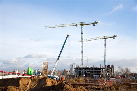 유압 용 지브 타워 크레인과 작업자가 콘크리트를 파운데이션에 부어 넣습니다 시멘트는 건설 현장에서 건물의 형태로 쏟아져 타워