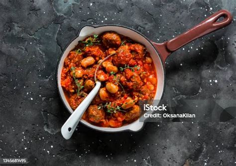 어두운 배경에 프라이팬에 향기로운 허브와 향신료와 토마토 소스에 미트볼과 콩 스튜 상단 보기 0명에 대한 스톡 사진 및 기타