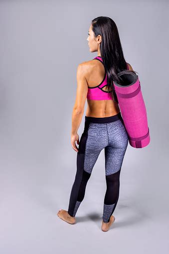 흰색 배경에 요가 매트를 들고 운동복을 입은 젊은 아름다운 여자가 고립되어 있다 스튜디오에서 운동하는 초상화에 서 있는 스포티한 여성 요가 라이프 스타일 훈련 35 39세에