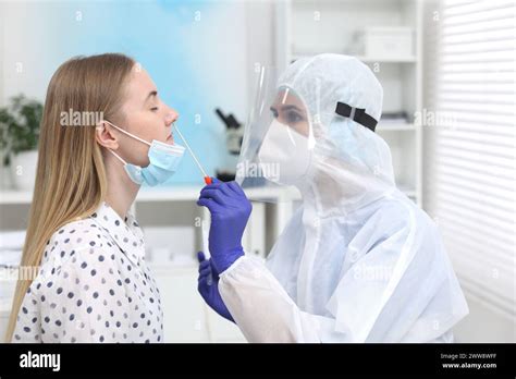 Laboratory Testing Doctor In Uniform Taking Sample From Patients Nose With Cotton Swab At