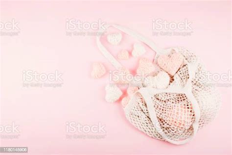 파스텔 배경에 흰색과 분홍색 니트 하트가 있는 재사용 가능한 쇼핑 네트 백 친환경 메쉬 쇼핑 코튼 백의 상단 전망 생태 제로