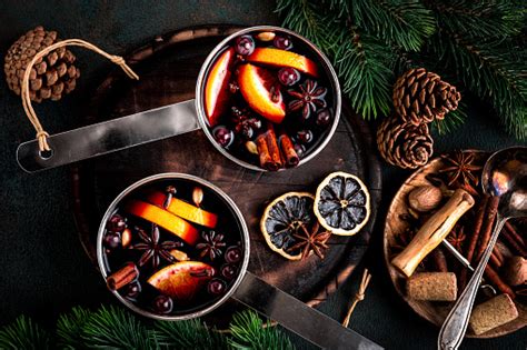 뜨거운 Mulled 와인 향신료 오렌지 두 냄비에 요리 하 고 크리스마스 전나무와 테이블에 크랜베리 어두운 배경에 잔 가지